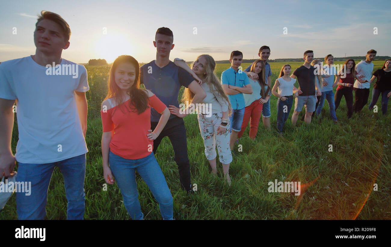 Silhouettes of nineteen friends holding hands on a sunset background ...