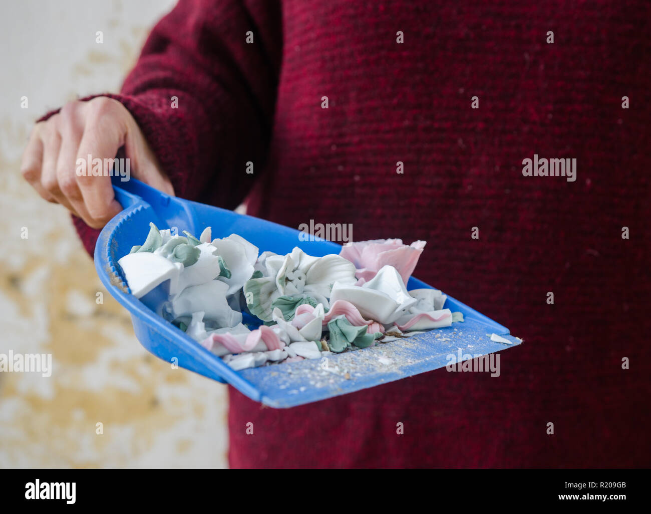 Broken porcelain tiles on a shovel next to the trash can - cleaning ...
