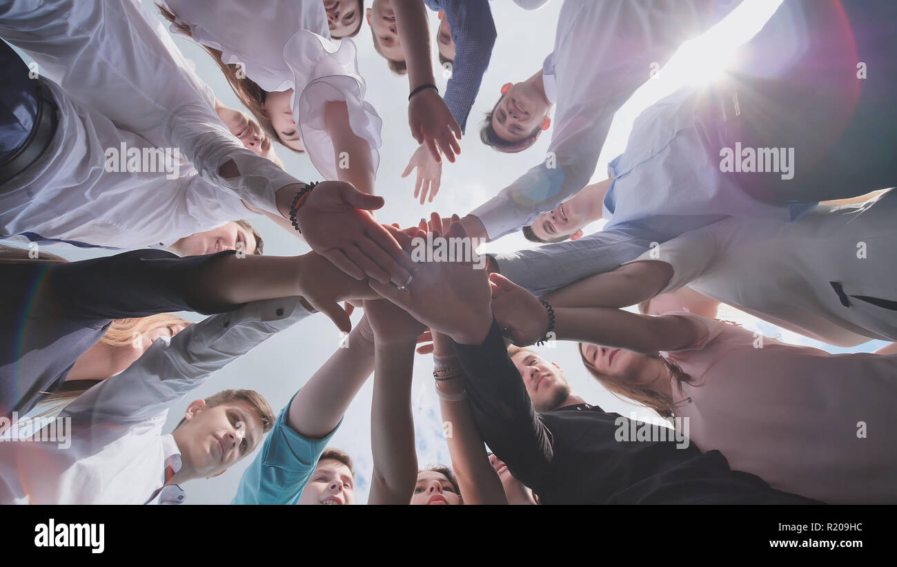 Students graduates gather around and lay their hands in a sign of ...