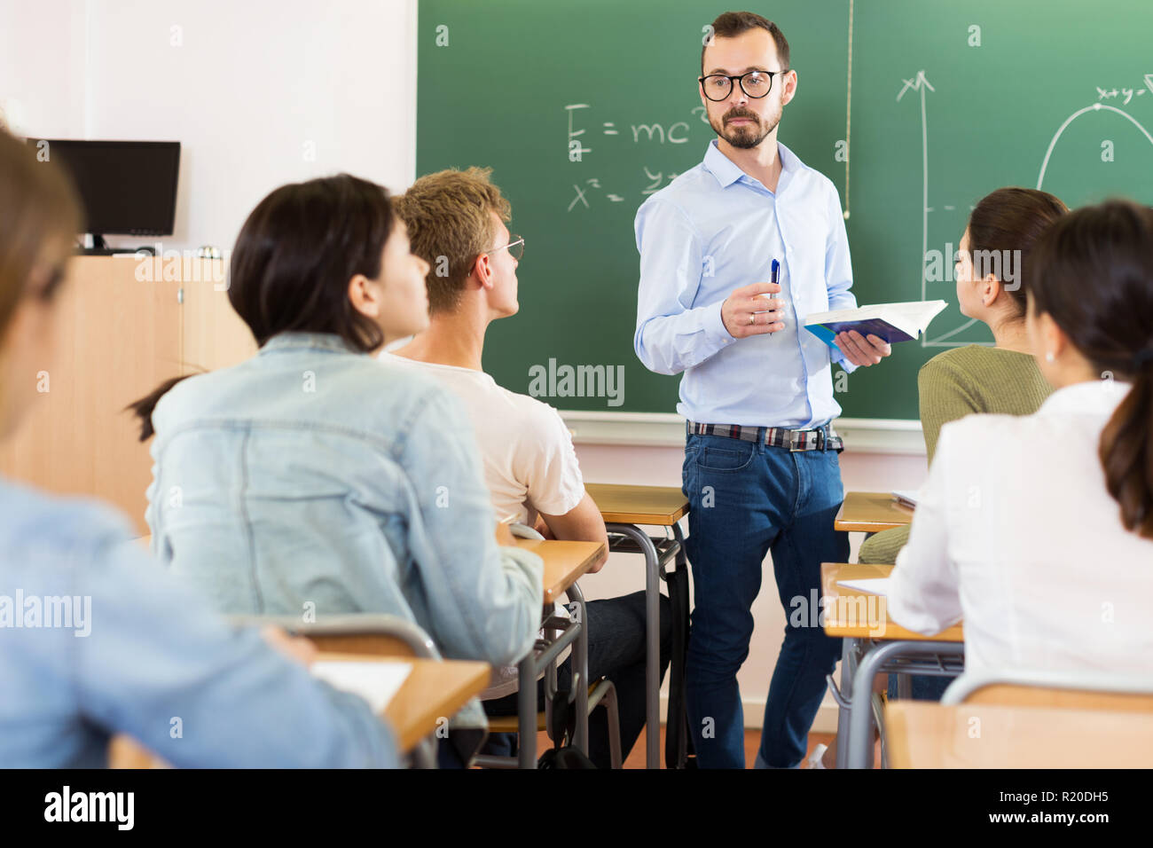 positive young teacher is giving lecture for students in the class ...