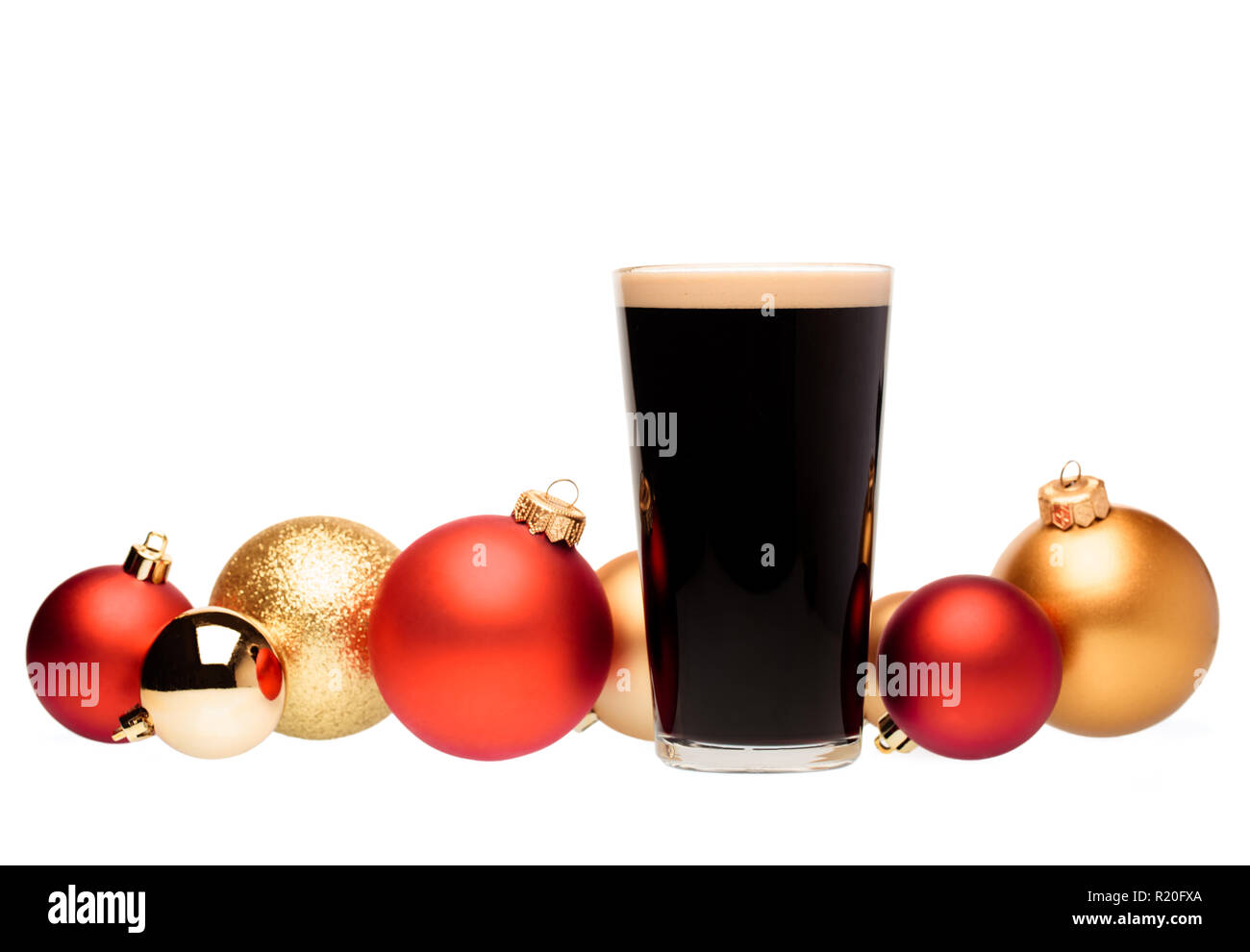 Full pint glass of dark beer or stout ale with christmas baubles on ...