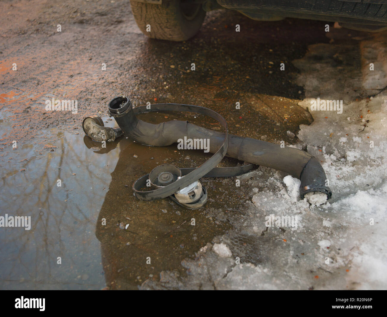 Broiken car parts laid in the dirt behind a car, outdoor cropped shot ...