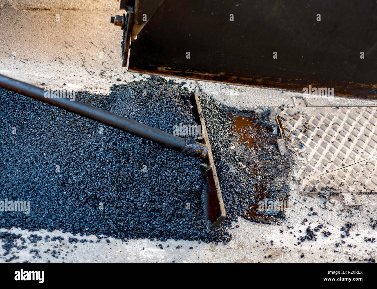 worker leveling fresh asphalt during asphalt pavement repair or ...