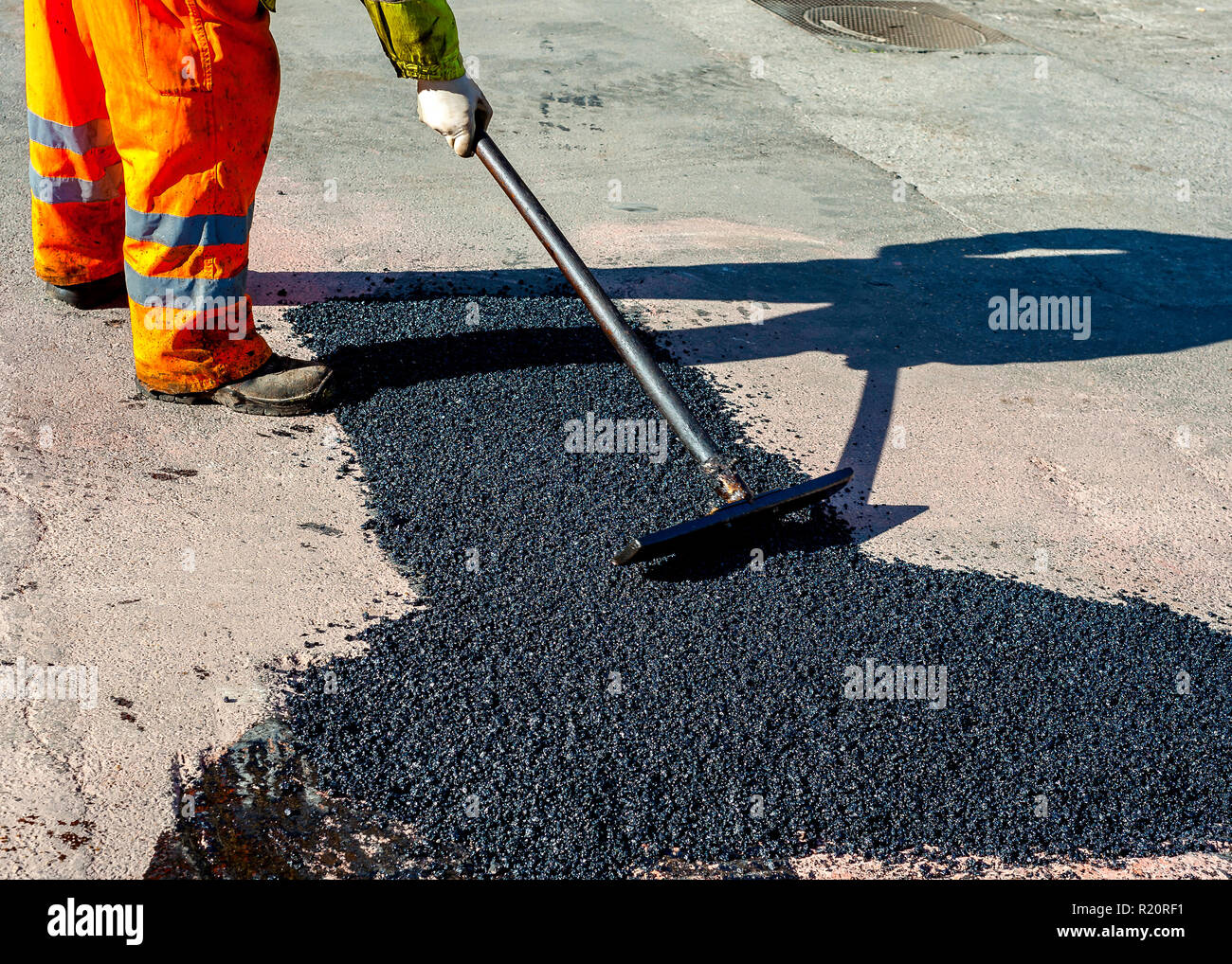 worker leveling fresh asphalt during asphalt pavement repair or ...