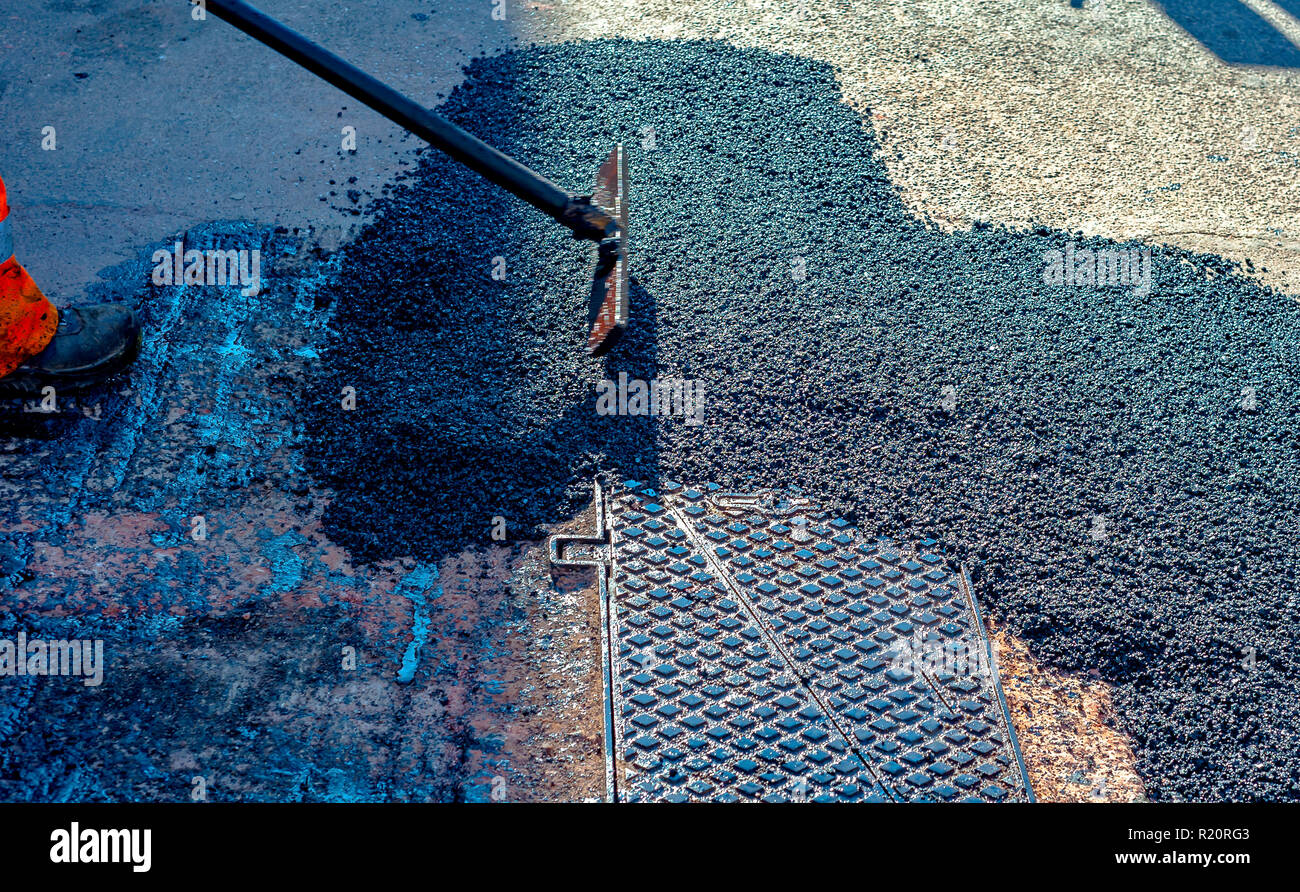 worker leveling fresh asphalt during asphalt pavement repair or ...