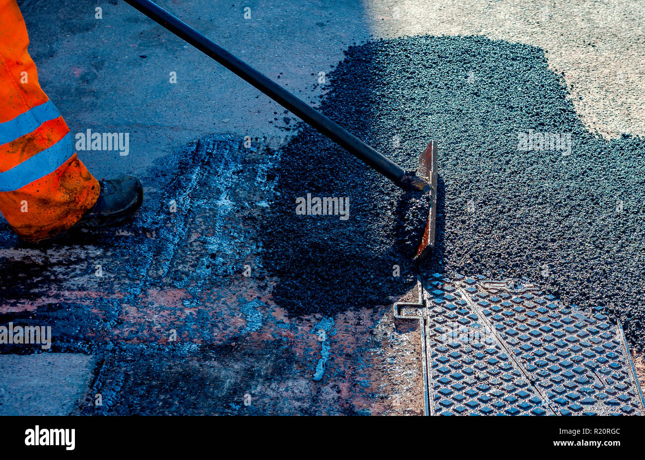 worker leveling fresh asphalt during asphalt pavement repair or ...