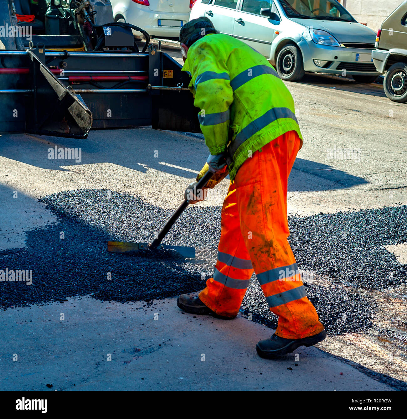 worker leveling fresh asphalt during asphalt pavement repair or ...