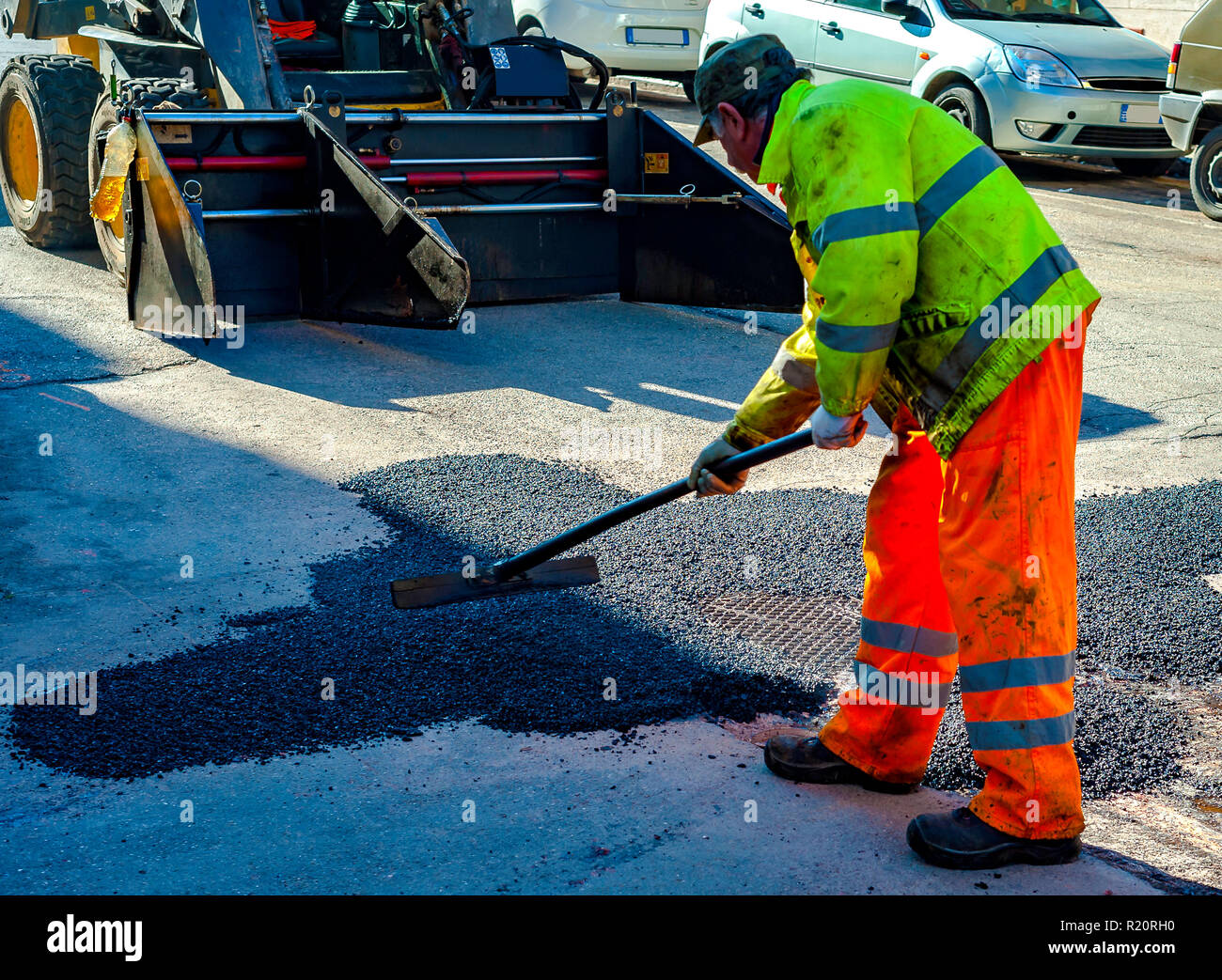worker leveling fresh asphalt during asphalt pavement repair or ...