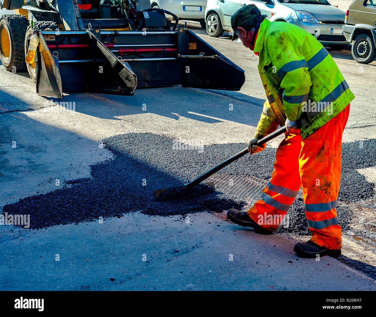 worker leveling fresh asphalt during asphalt pavement repair or ...