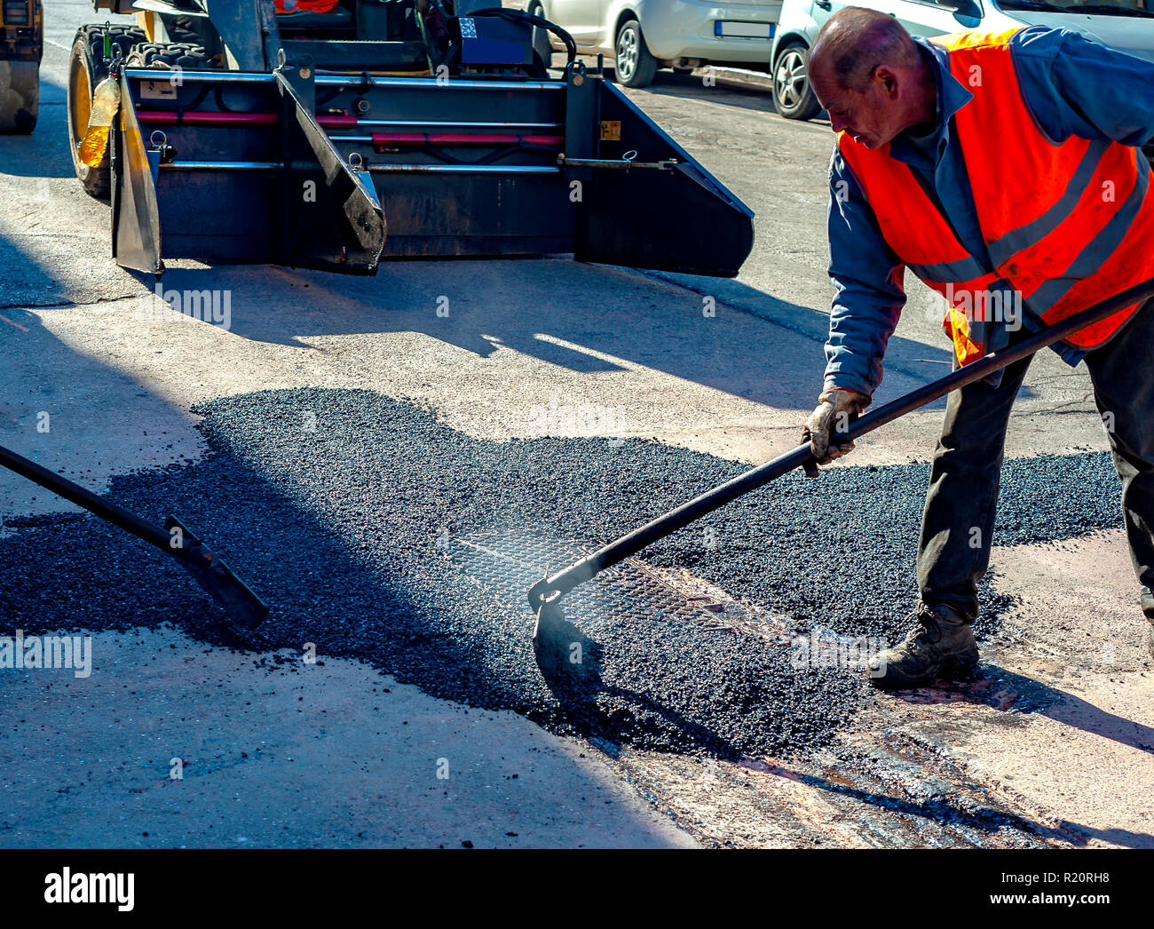 worker leveling fresh asphalt during asphalt pavement repair or ...