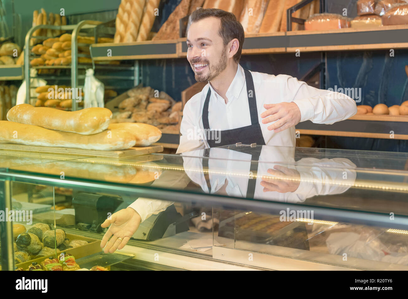 positive american male shop assistant demonstrating fresh delicious ...