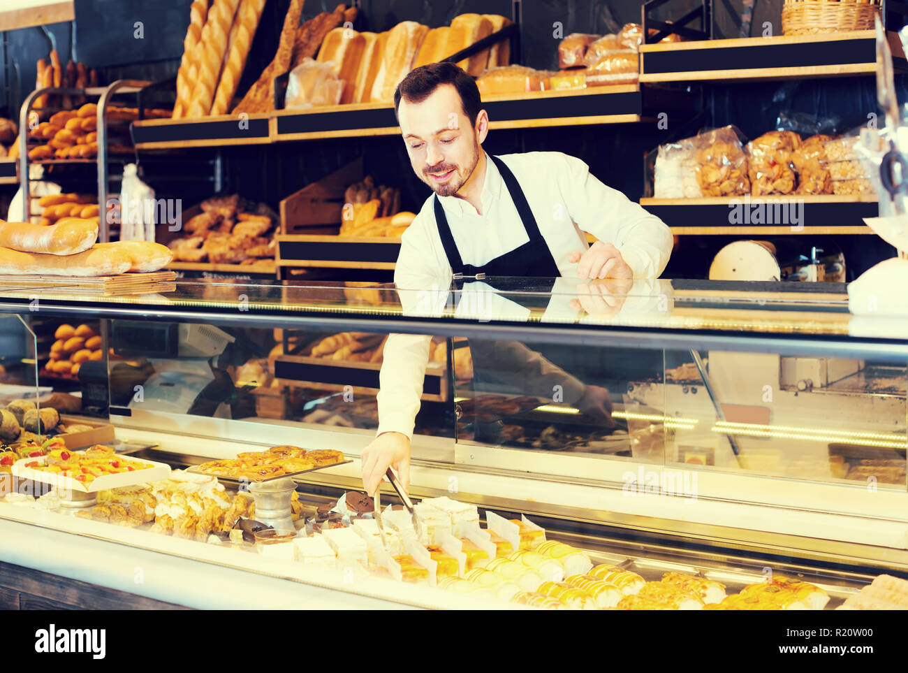 Young salesman shows the types of cakes in a bakery Stock Photo - Alamy