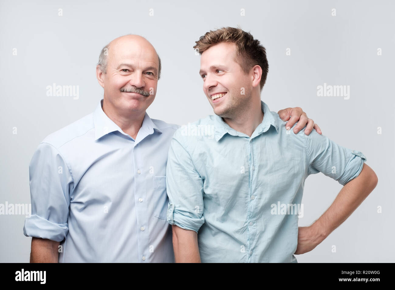 Senior father is proud of his mature son. He is holding his shoulder ...