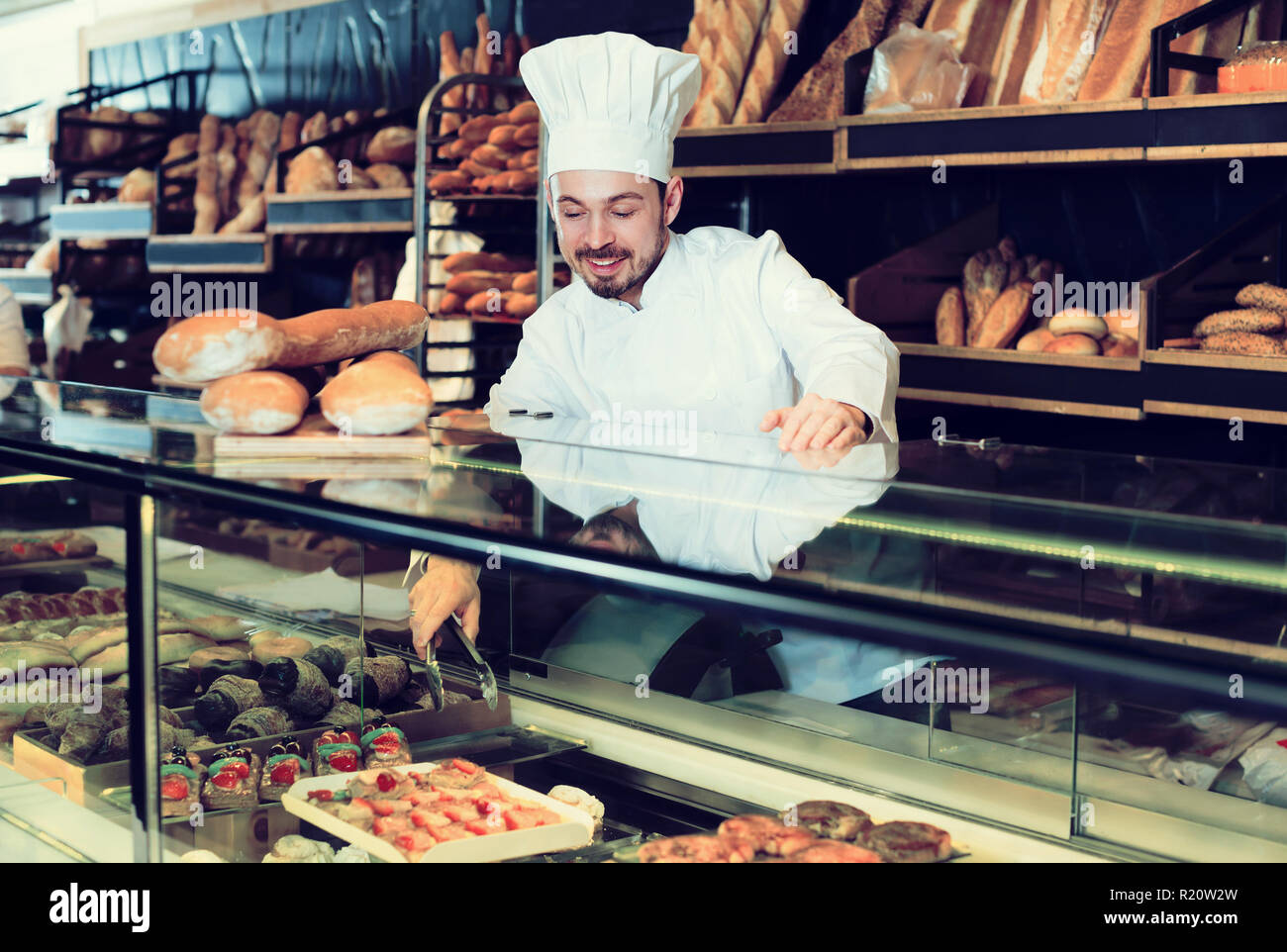 Optimistic male baker showing assortment of bakery Stock Photo - Alamy