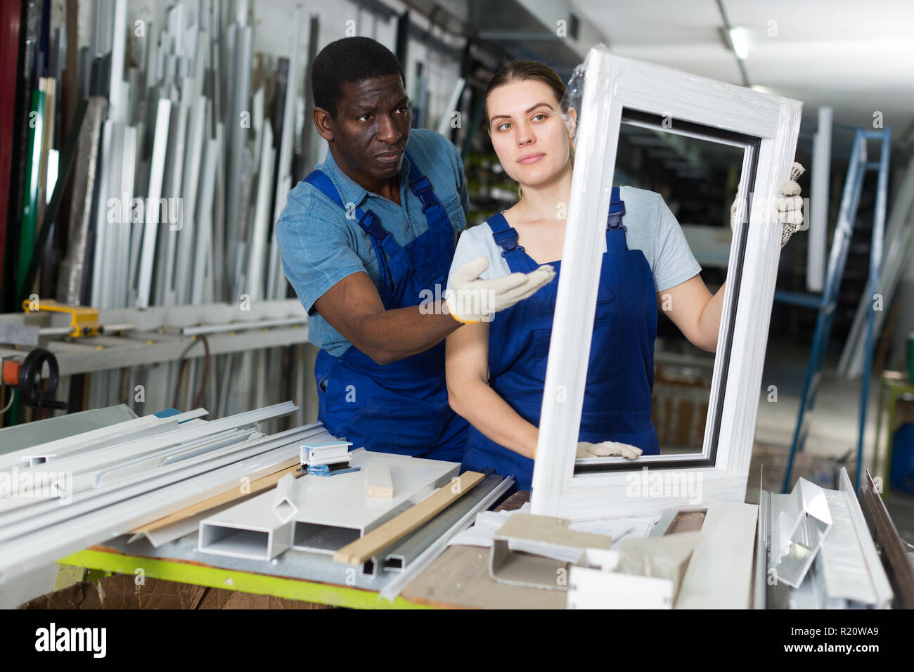 Portrait of man and woman worker who are standing with window frames in ...