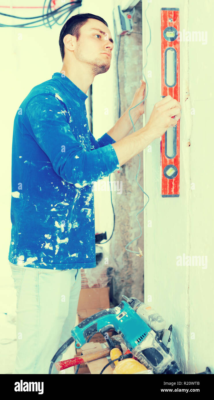 Worker is measuring angle of wall with level during house renovation ...