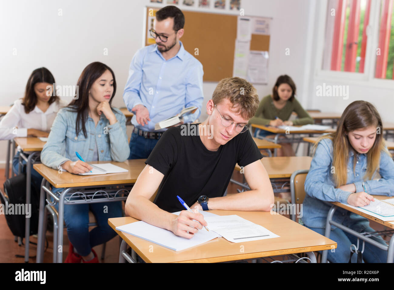Young boy is writing test and thinking about questions at the desk in ...