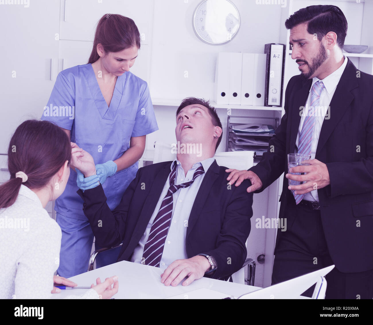 Businessman in fainting receiving first aid at workplace in office ...