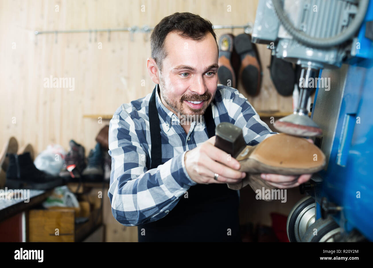 Positive man worker restore footwear in repair workplace Stock Photo ...