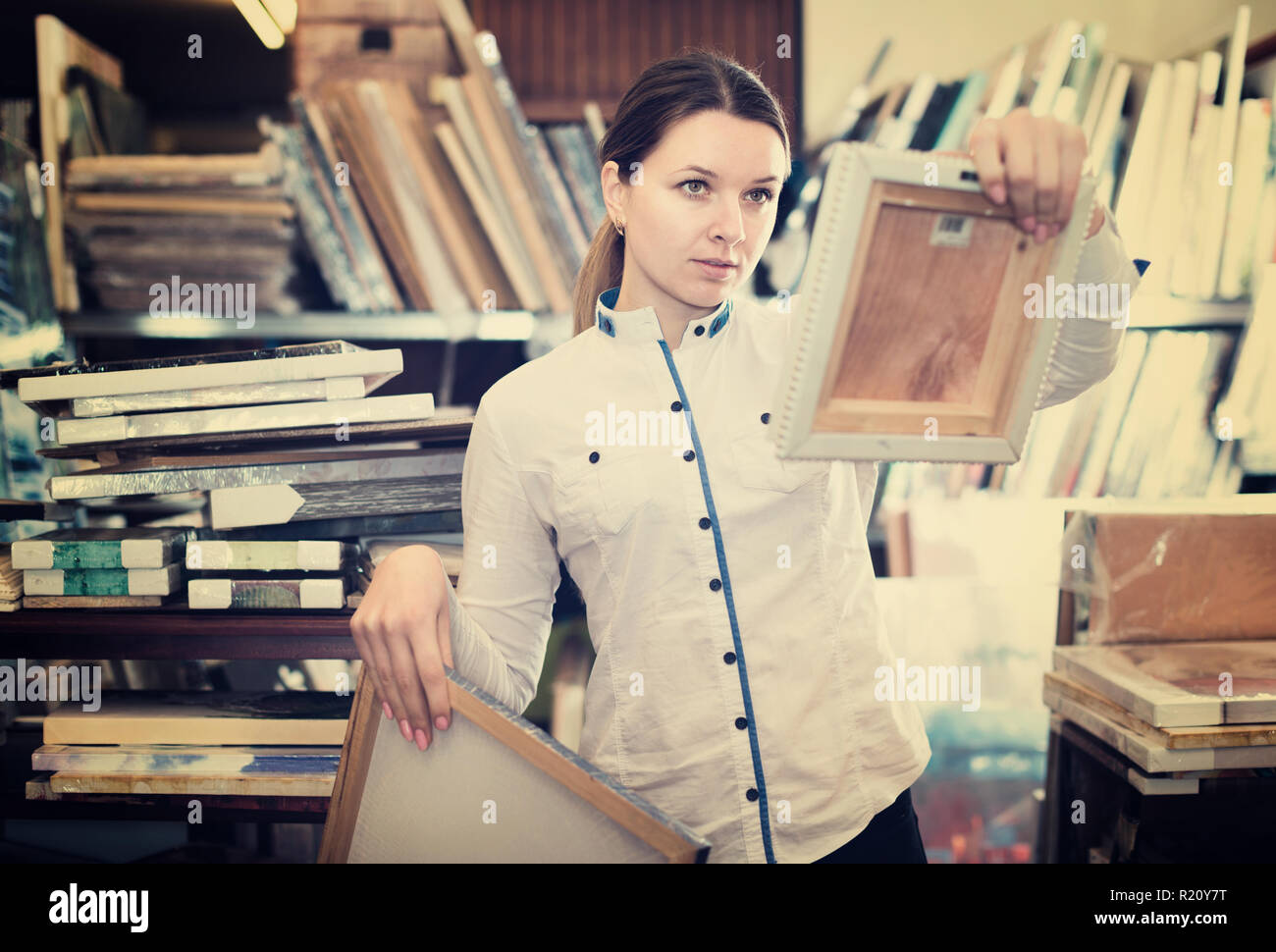 Satisfied pleasant smiling girl is choosing modern picture in furniture ...