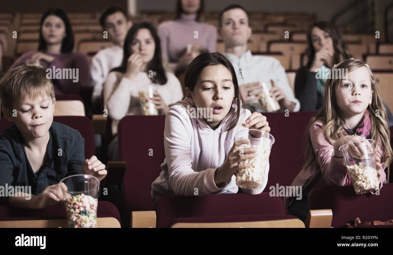 Group of different age people eating popcorn during movie in cinema ...