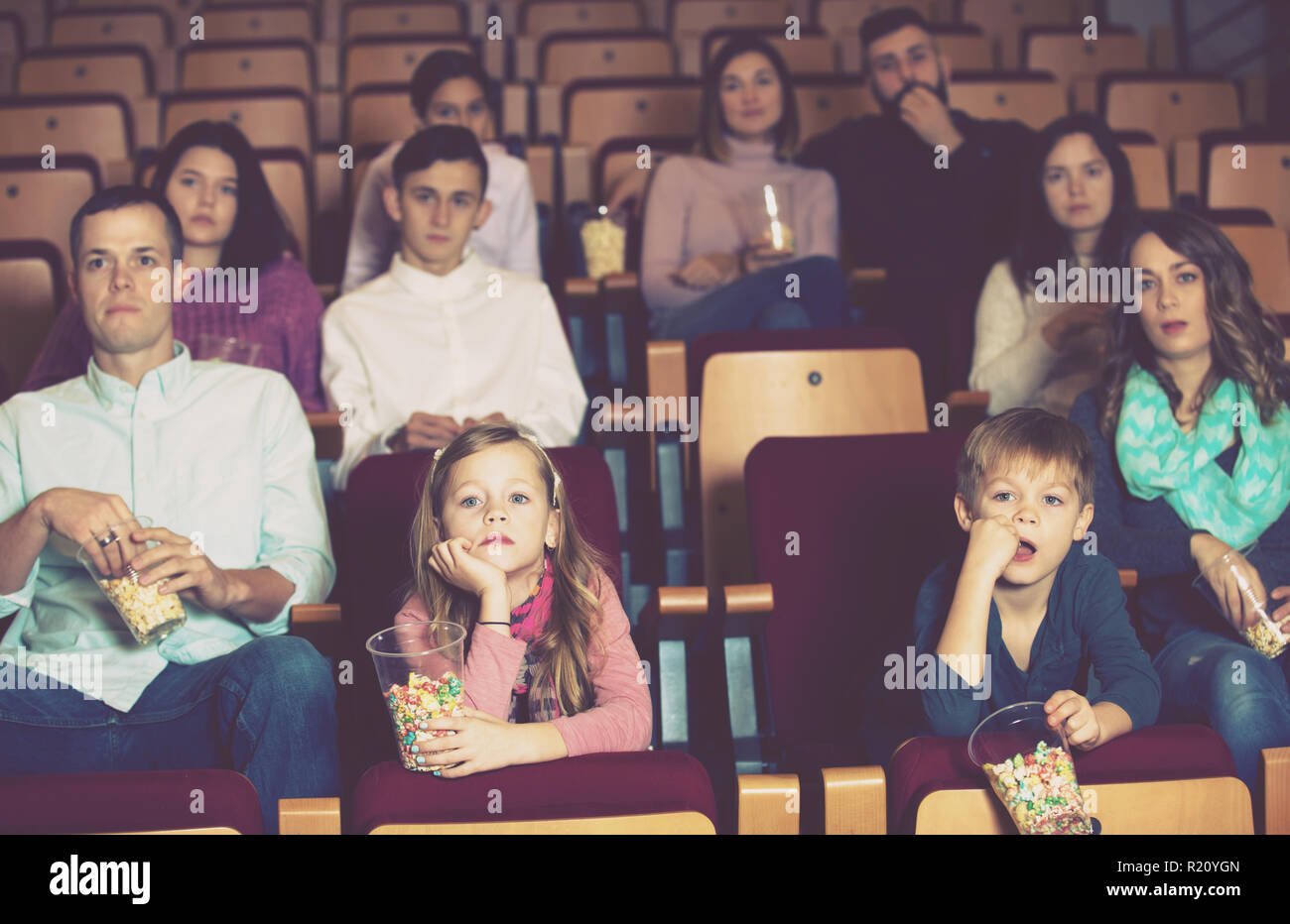 Group of people eating popcorn while watching movie in cinema interior ...