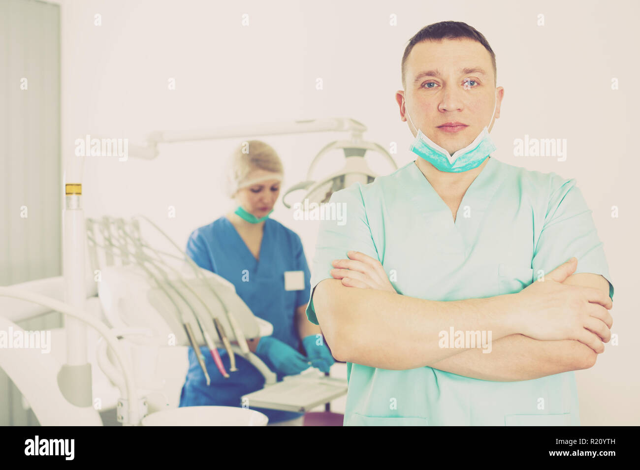 Portrait of professional male dentist with arms crossed in office with ...