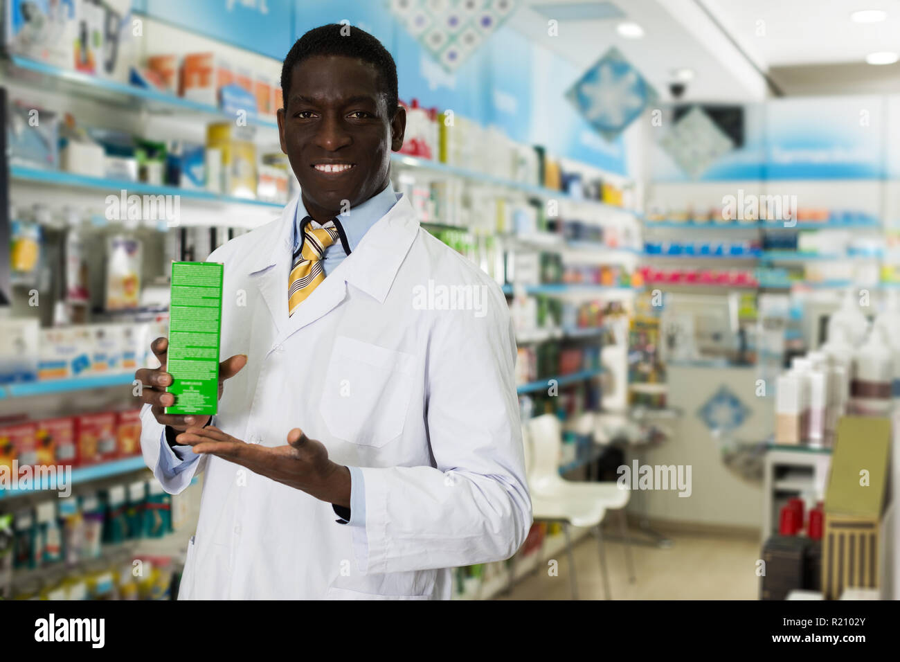 Positive young African American male pharmacist offering medication in ...