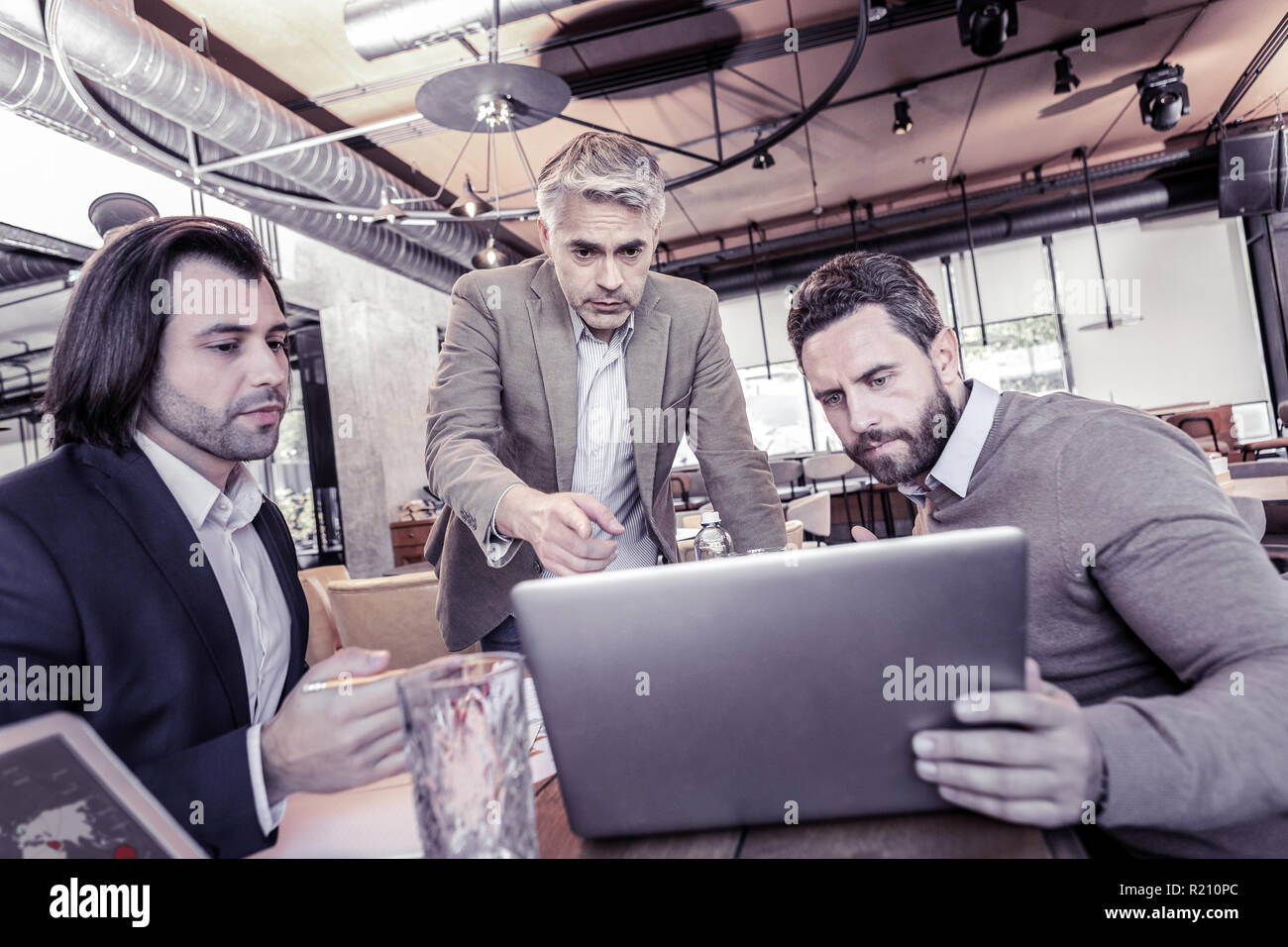 Attentive men looking at screen of computer Stock Photo - Alamy