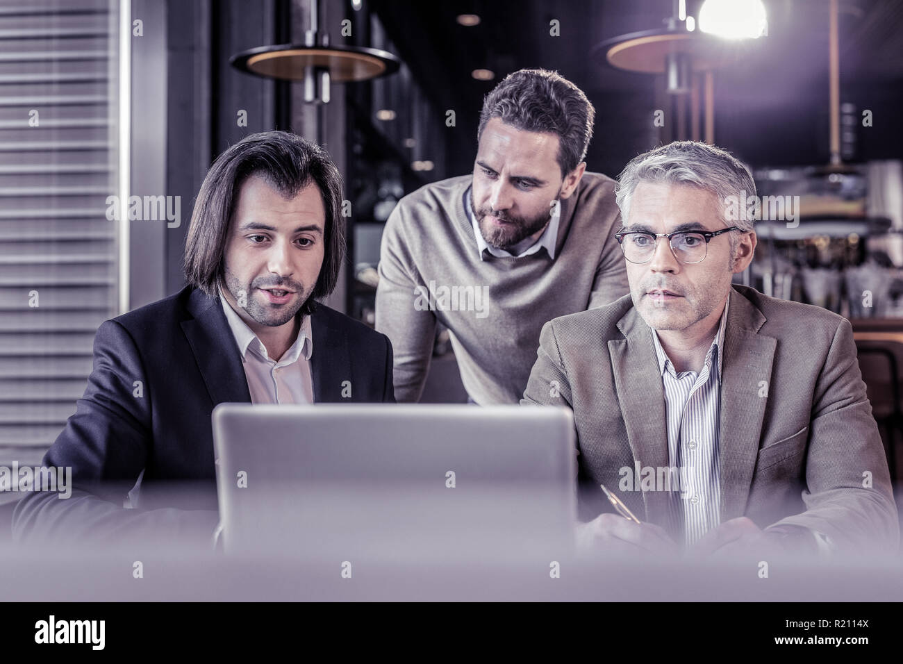 Cheerful longhaired man staring at screen of laptop Stock Photo - Alamy
