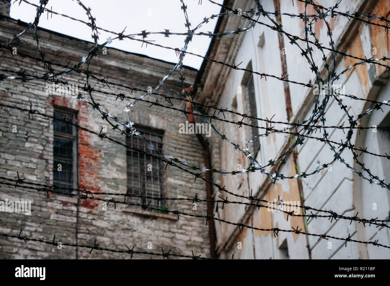 Old ramshackle decrepit walls of soviet prison through barbed wire ...