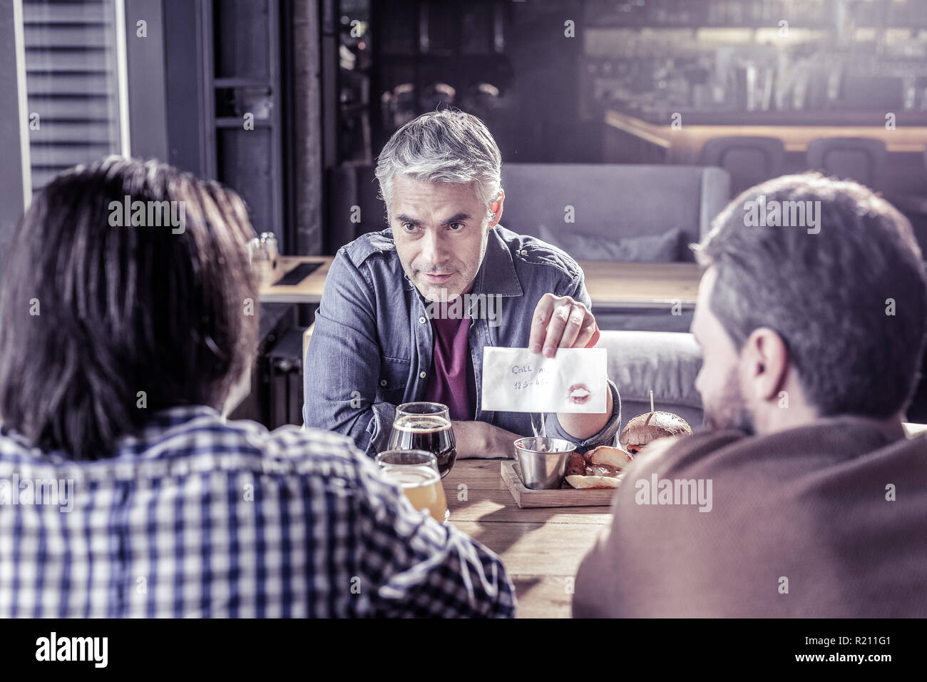 Concentrated man showing romantic notes to friends Stock Photo - Alamy