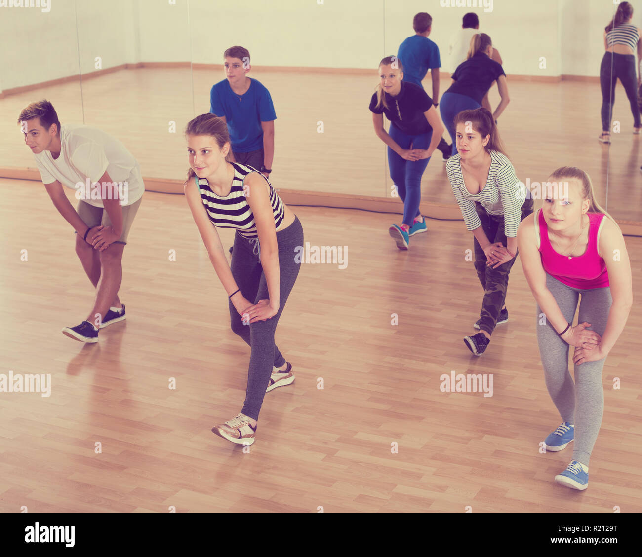 Group of teenage students with instructor stretching at dance class ...