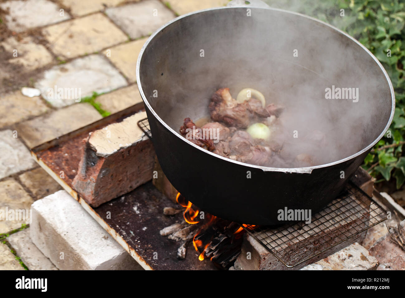 Lamb with onion boiling in a cauldron on bonfire. Preparing of Chorba ...