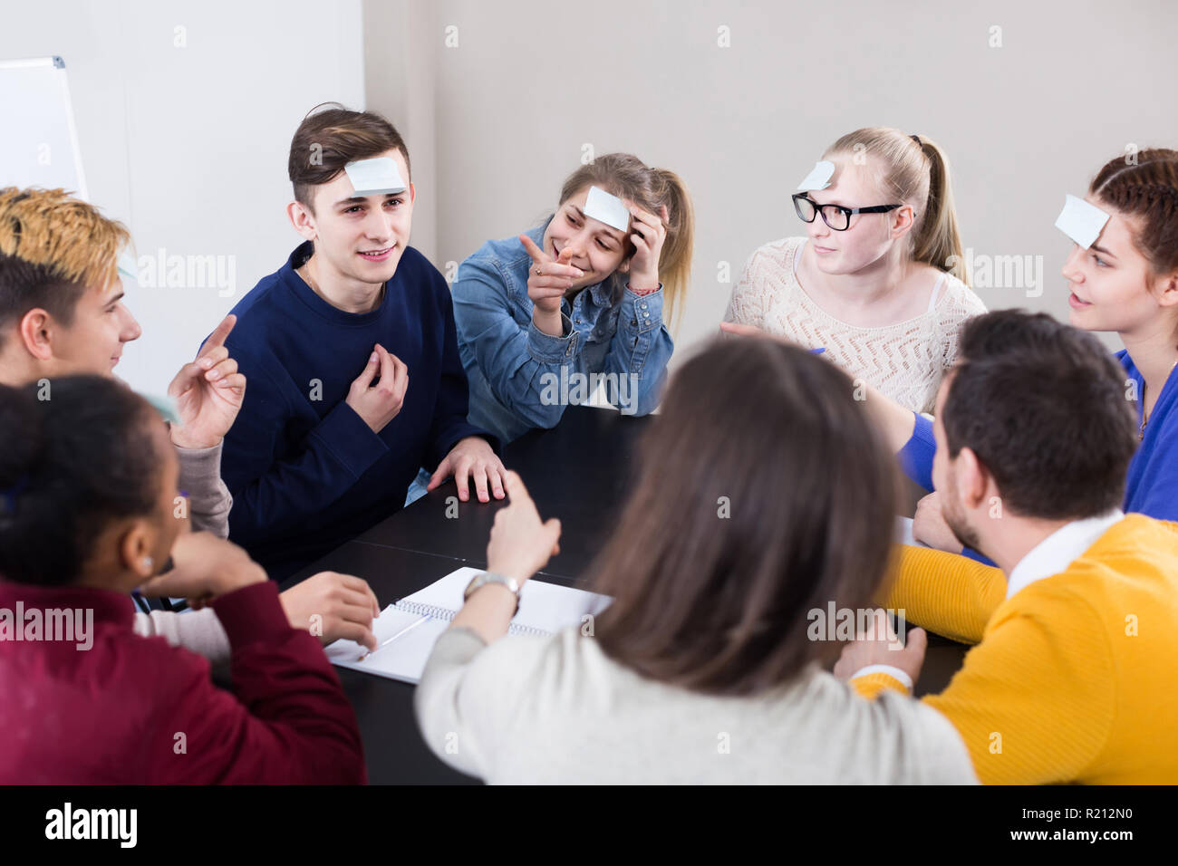 happy european classmates having round of guess-who game during class ...