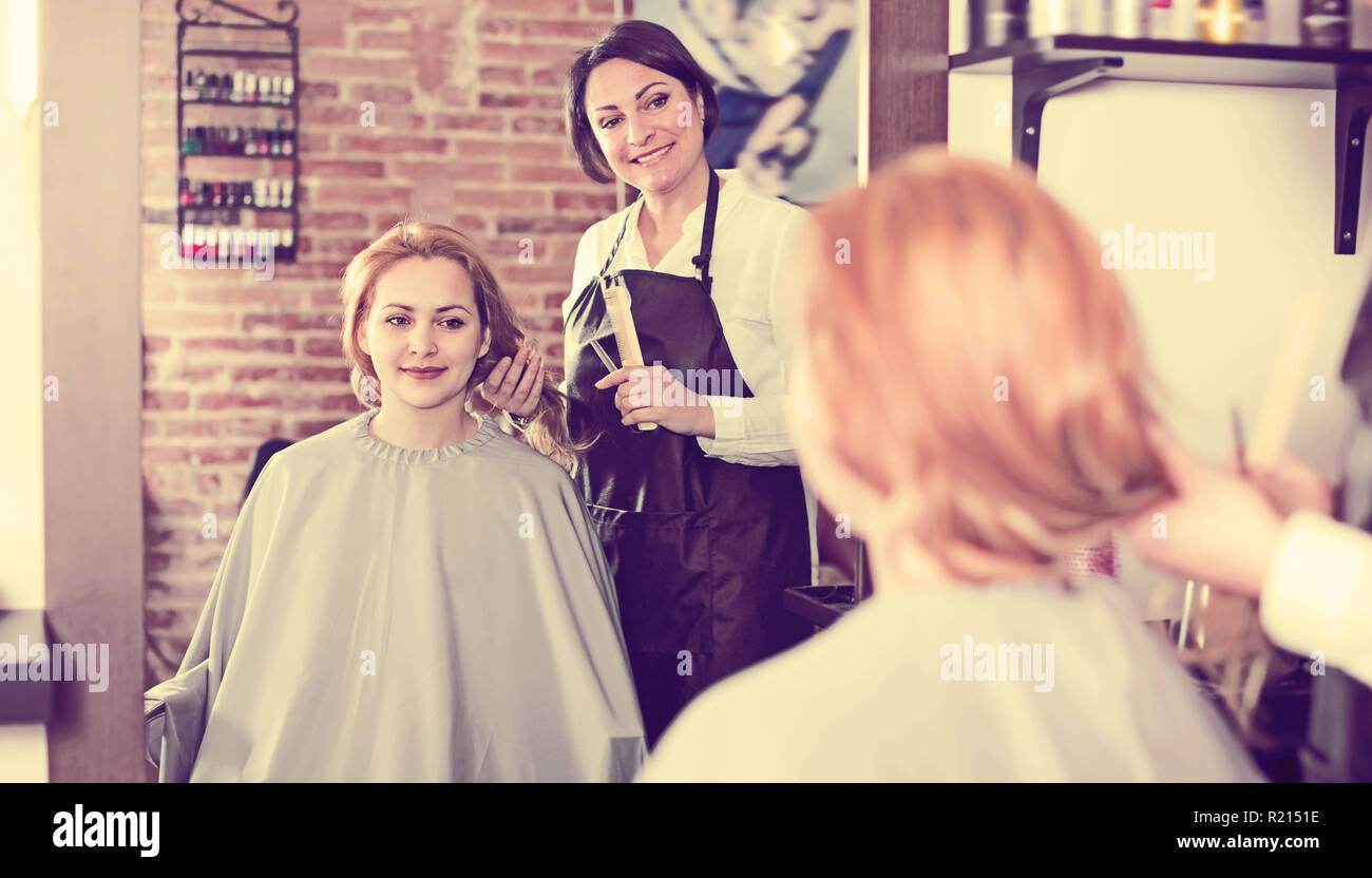 Young woman in hairdressing salon decides with master how to cut her ...