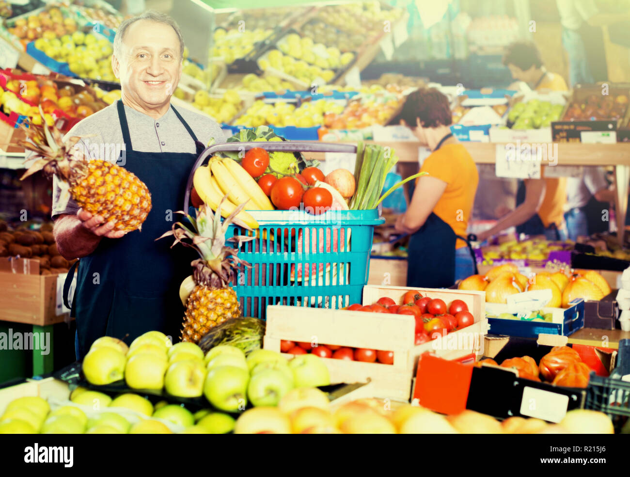Smiling cheerful positive man seller is standing with basket with ...