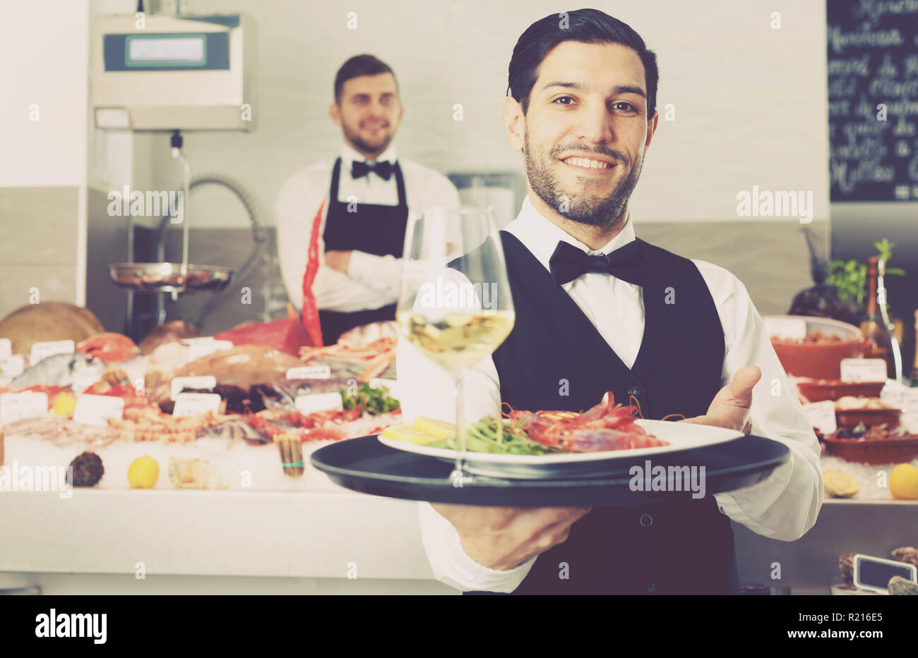 Handsome bearded waiter standing with serving tray in fish restaurant ...