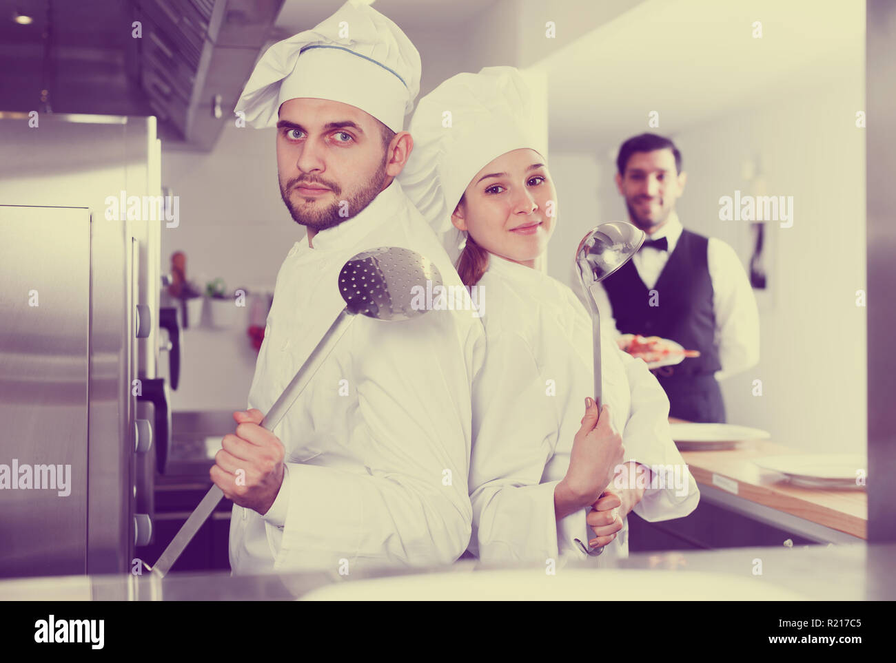 Two positive chefs in uniform in kitchen of fish restaurant on ...