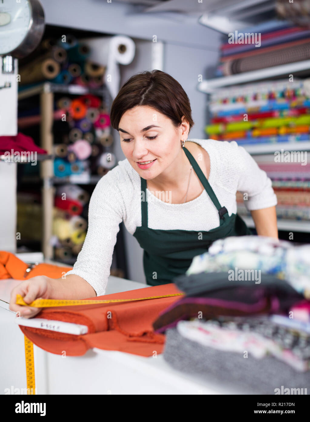 Female shop assistant measuring piece of cloth at drapery shop Stock ...