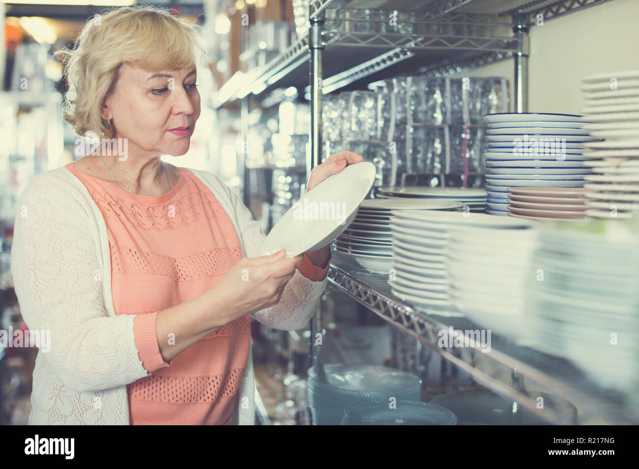 mature woman choosing clay plates for eating in the dishes shop Stock ...
