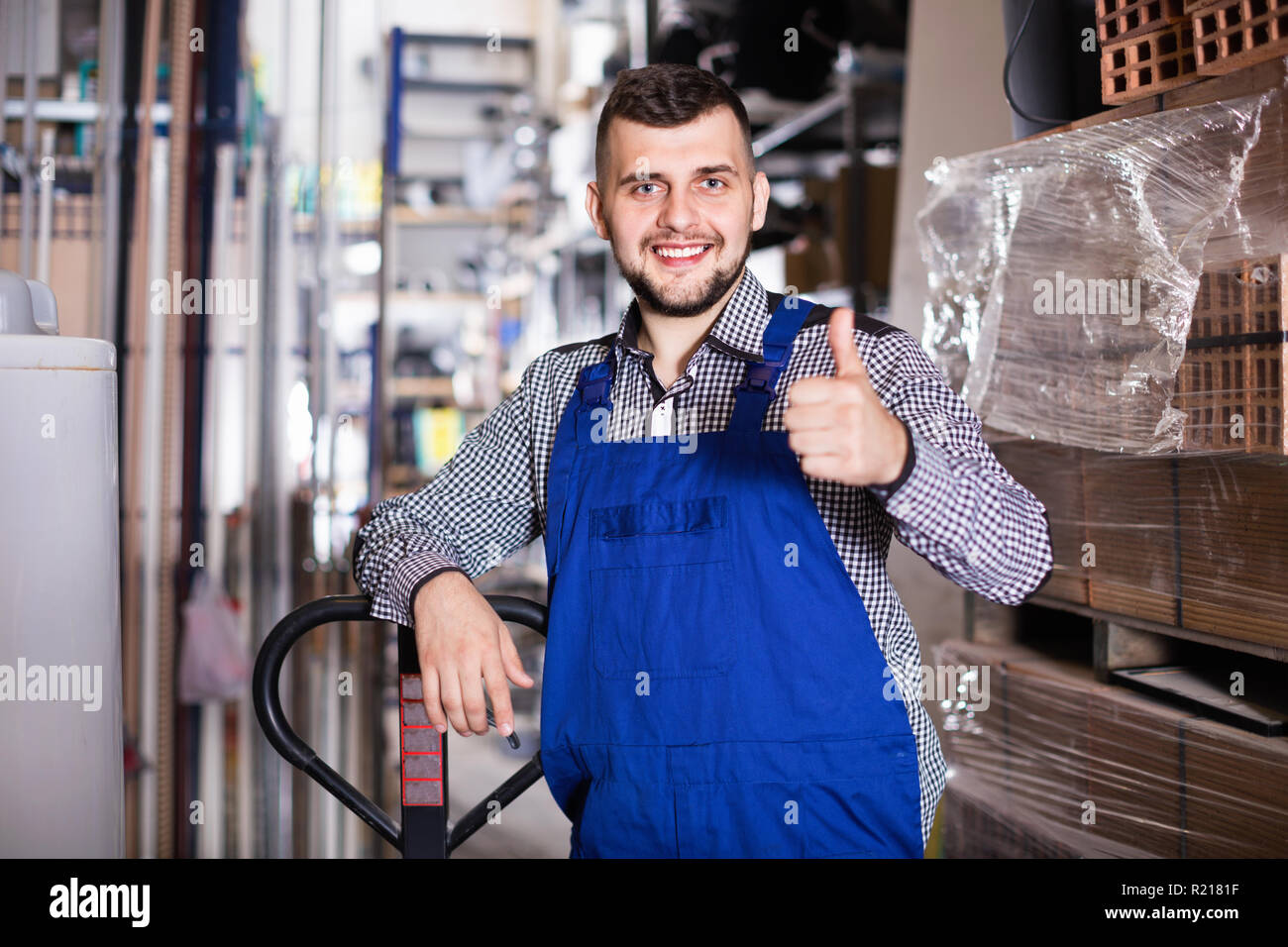 Friendly smiling working man demonstrating his workplace at workshop ...