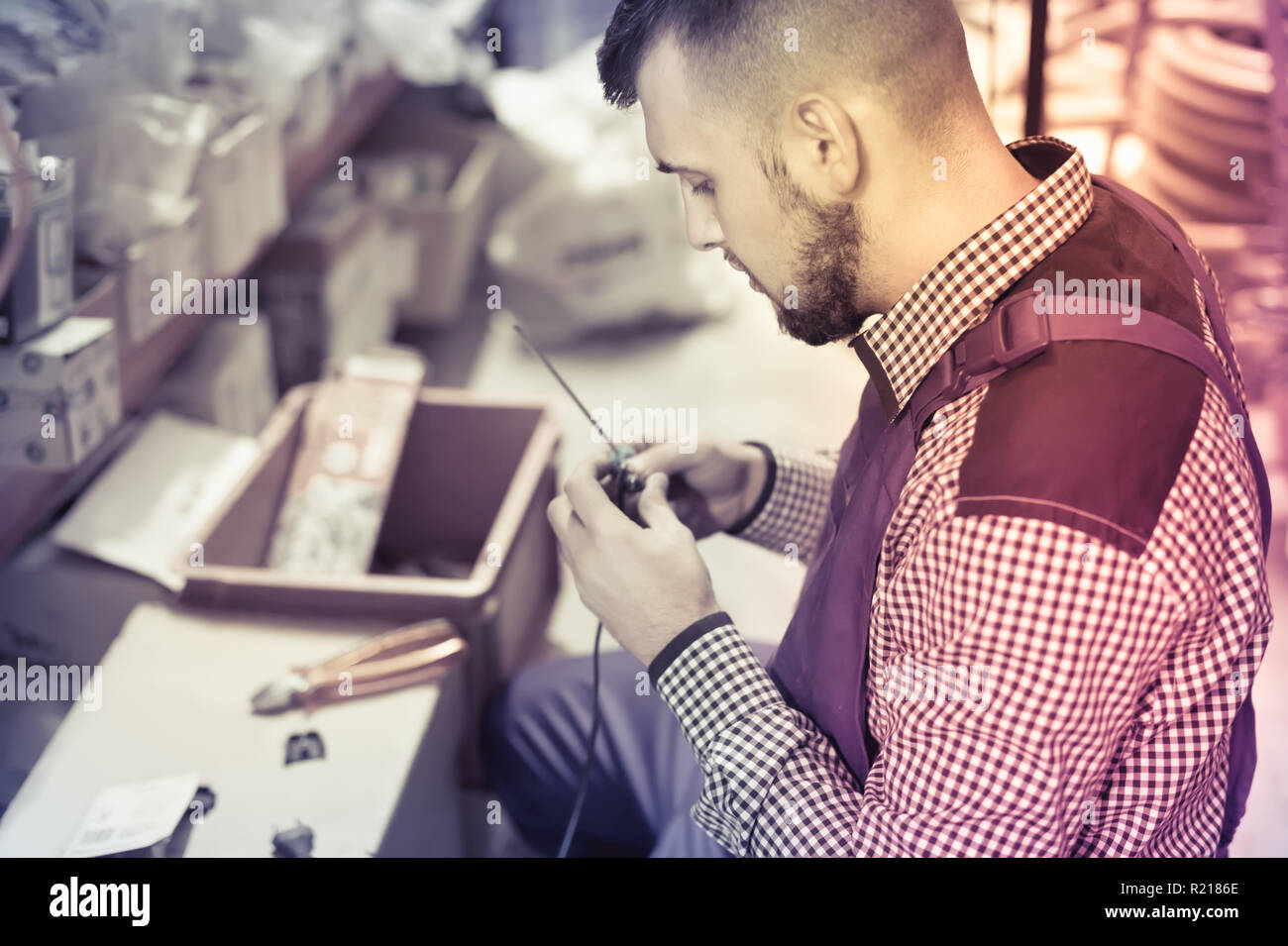 Young male worker using his tools for repairing plug in workshop Stock ...