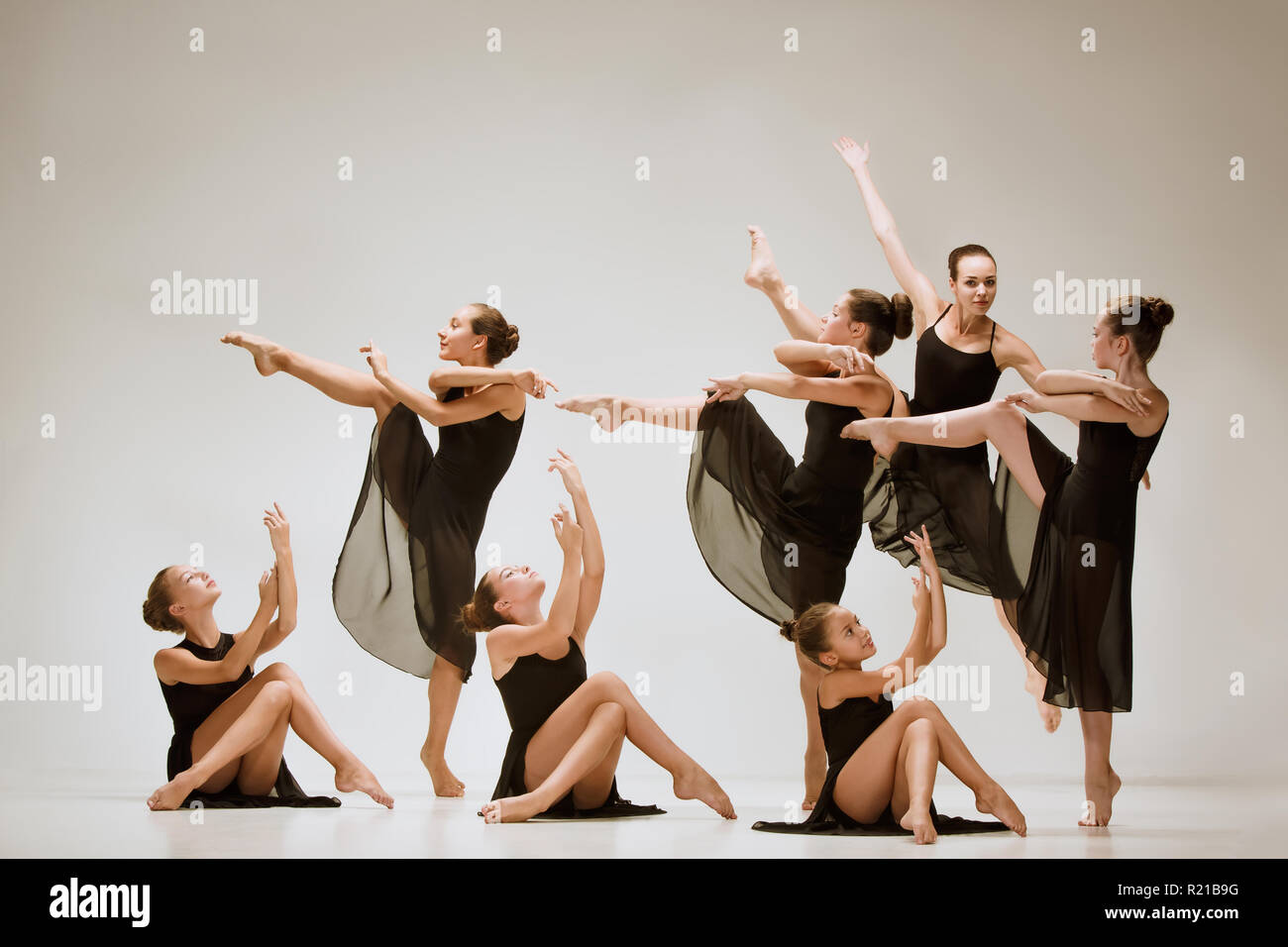 The group of modern ballet dancers dancing on gray studio background ...