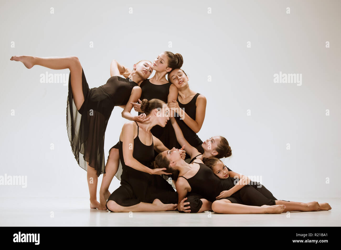 The group of modern ballet dancers dancing on gray studio background ...