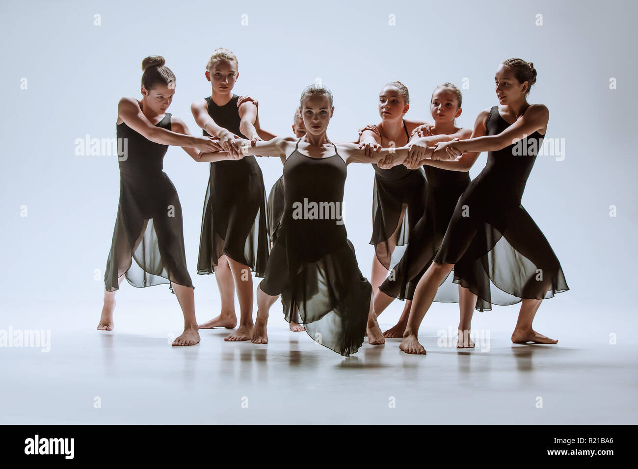 The group of modern ballet dancers dancing on gray studio background ...