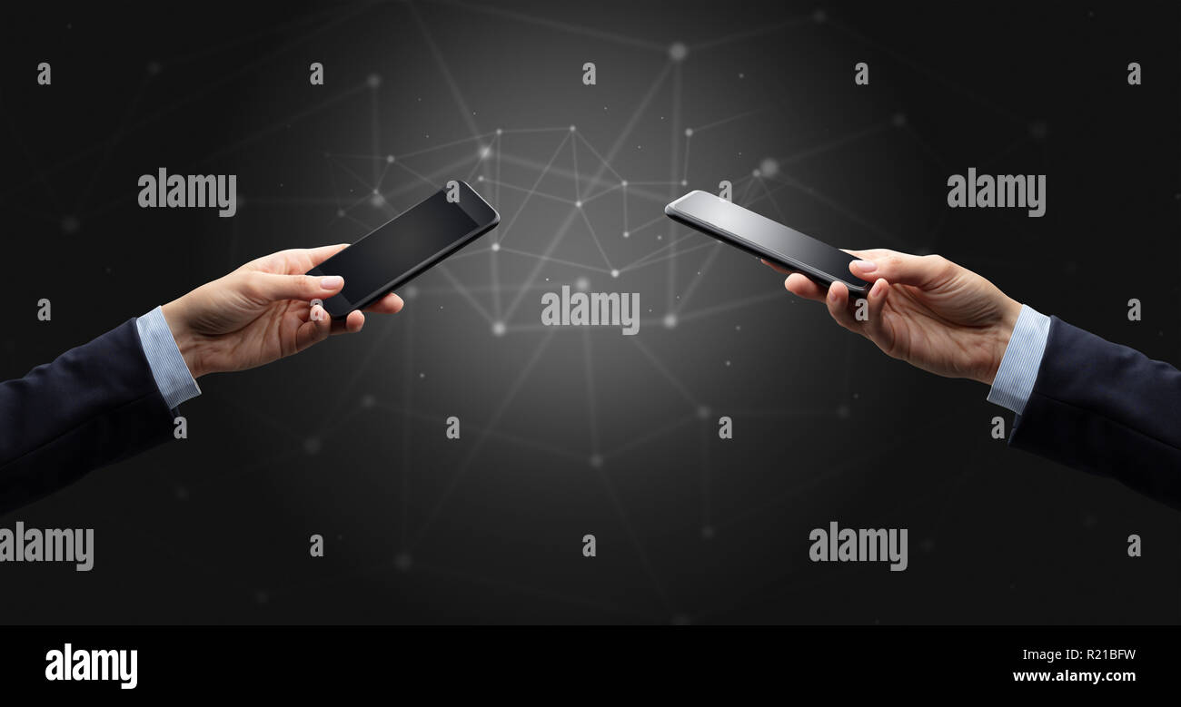 Close up of two hands holding smartphones to each other, wireless ...