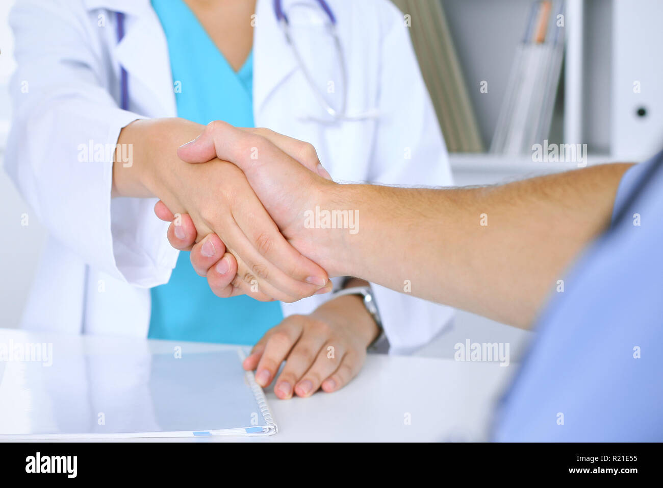 Two doctors shaking hands to each other at meeting. Teamwork and ...