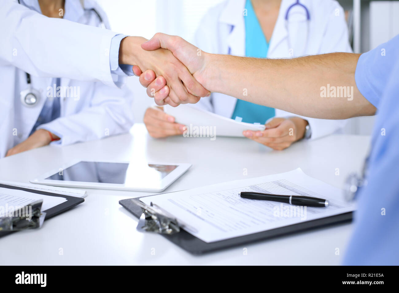 Two doctors shaking hands to each other at meeting. Teamwork and ...