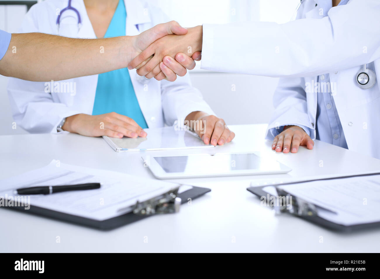 Two doctors shaking hands to each other at meeting. Teamwork and ...